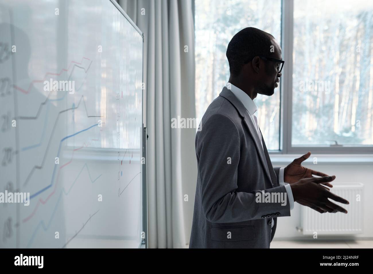 Young confident black man in grey suit explaining information to ...