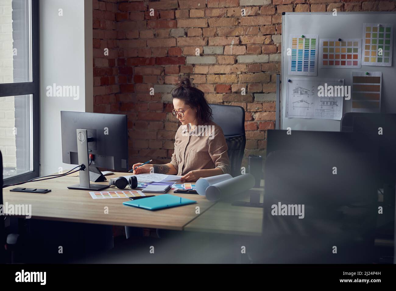 Concentrated woman, professional designer looking through papers while ...