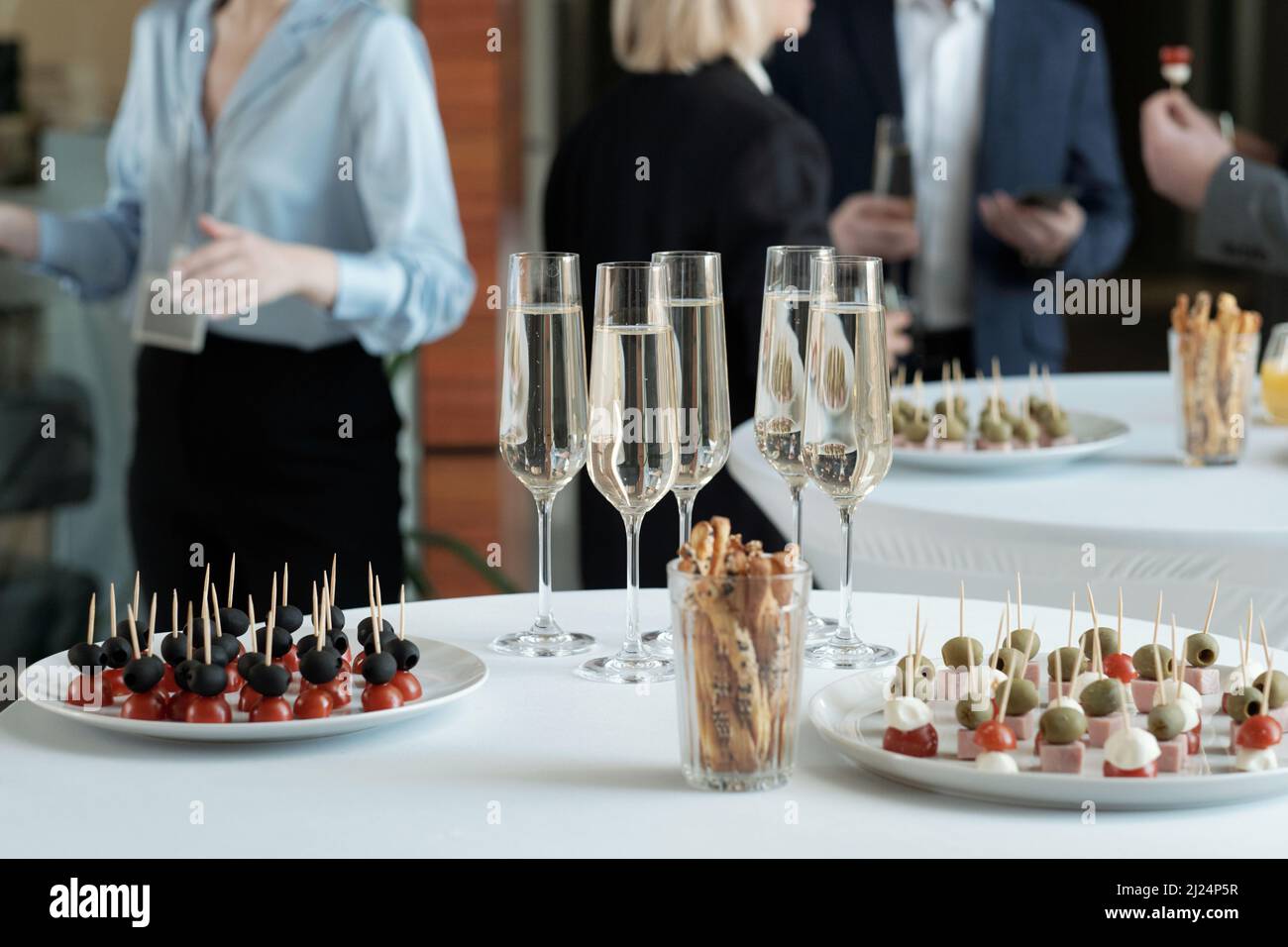 Two plates with appetizing canape and group of champagne in flutes ...