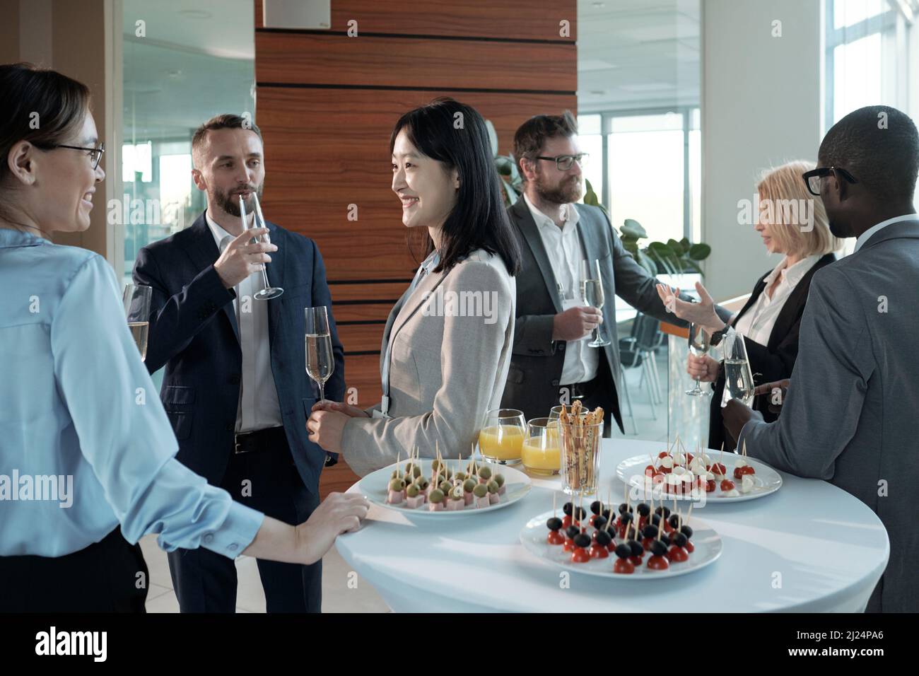 Three cheerful intercultural colleagues with champagne having ...
