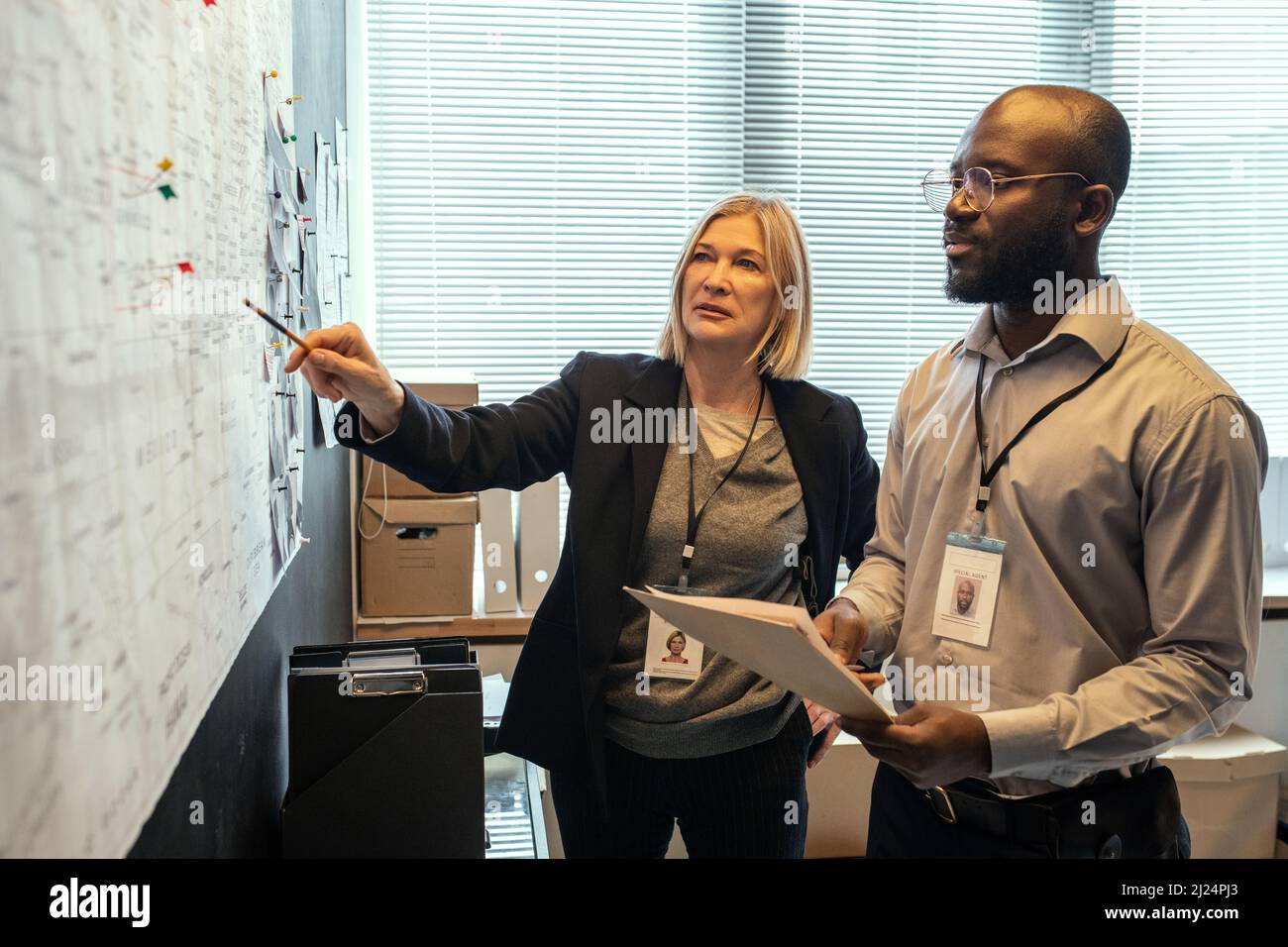 Confident mature female FBI agent pointing at map while showing male ...