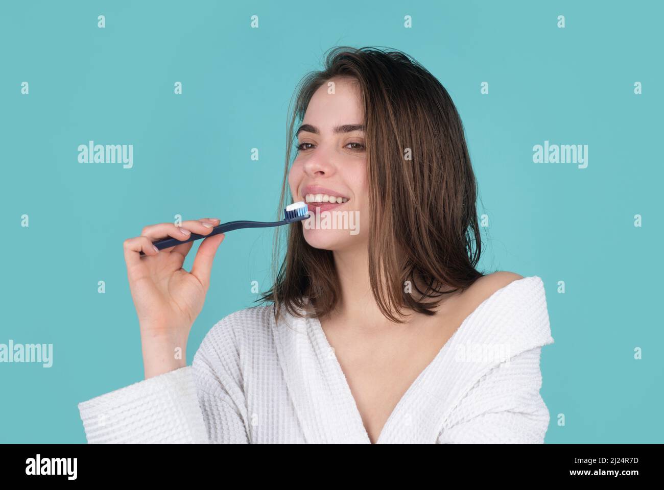 Young woman brushing teeth. Happy funny girl brush her teeth on isolated background. Beautiful ...
