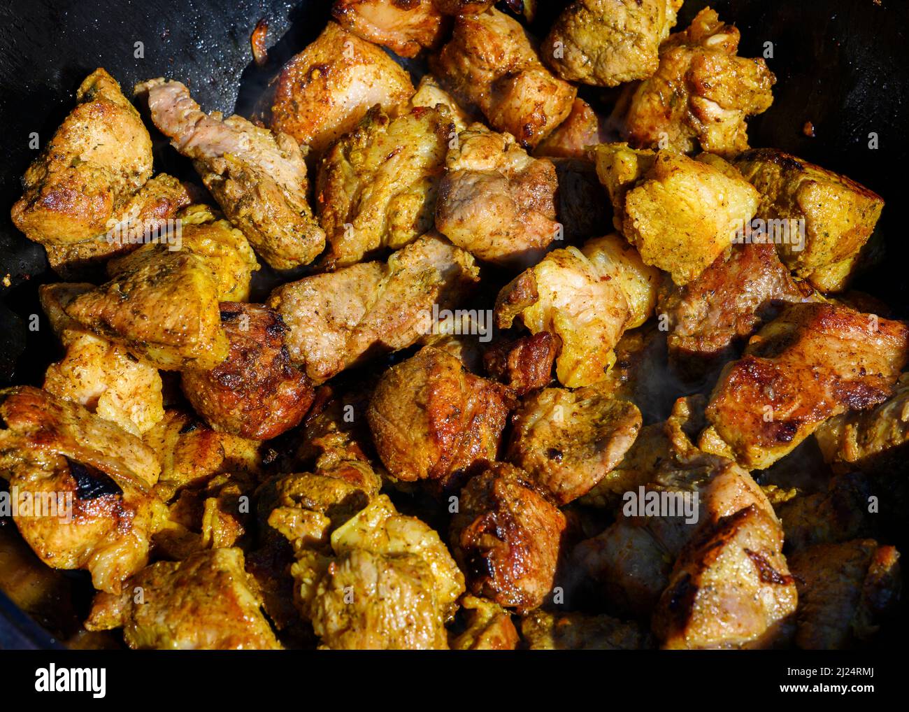 The meat is fried in a cast iron pot Stock Photo - Alamy