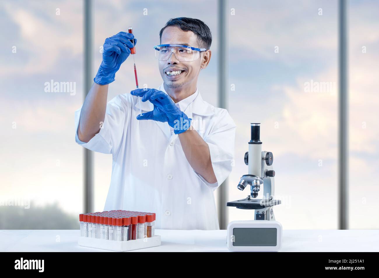 Asian nerd scientist taking a sample tube with a syringe and a ...