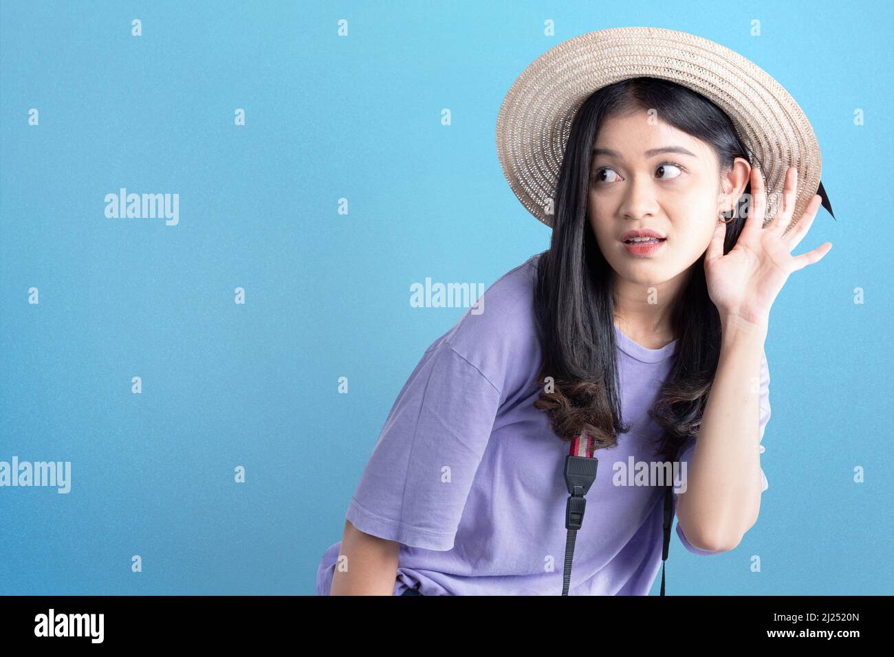 Asian woman with hat and camera hearing something with colored ...