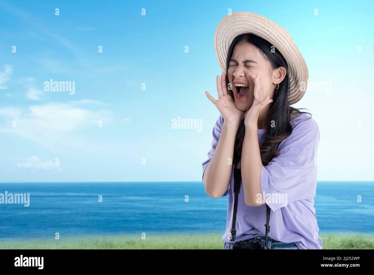 Asian woman with hat and camera yelling something with blue sky ...