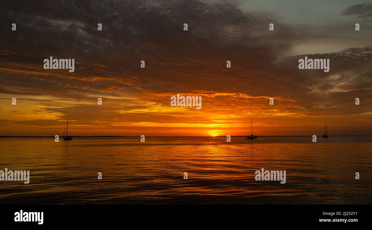 Sunset with large yellow sun under the sea surface. Calm ocean with ...