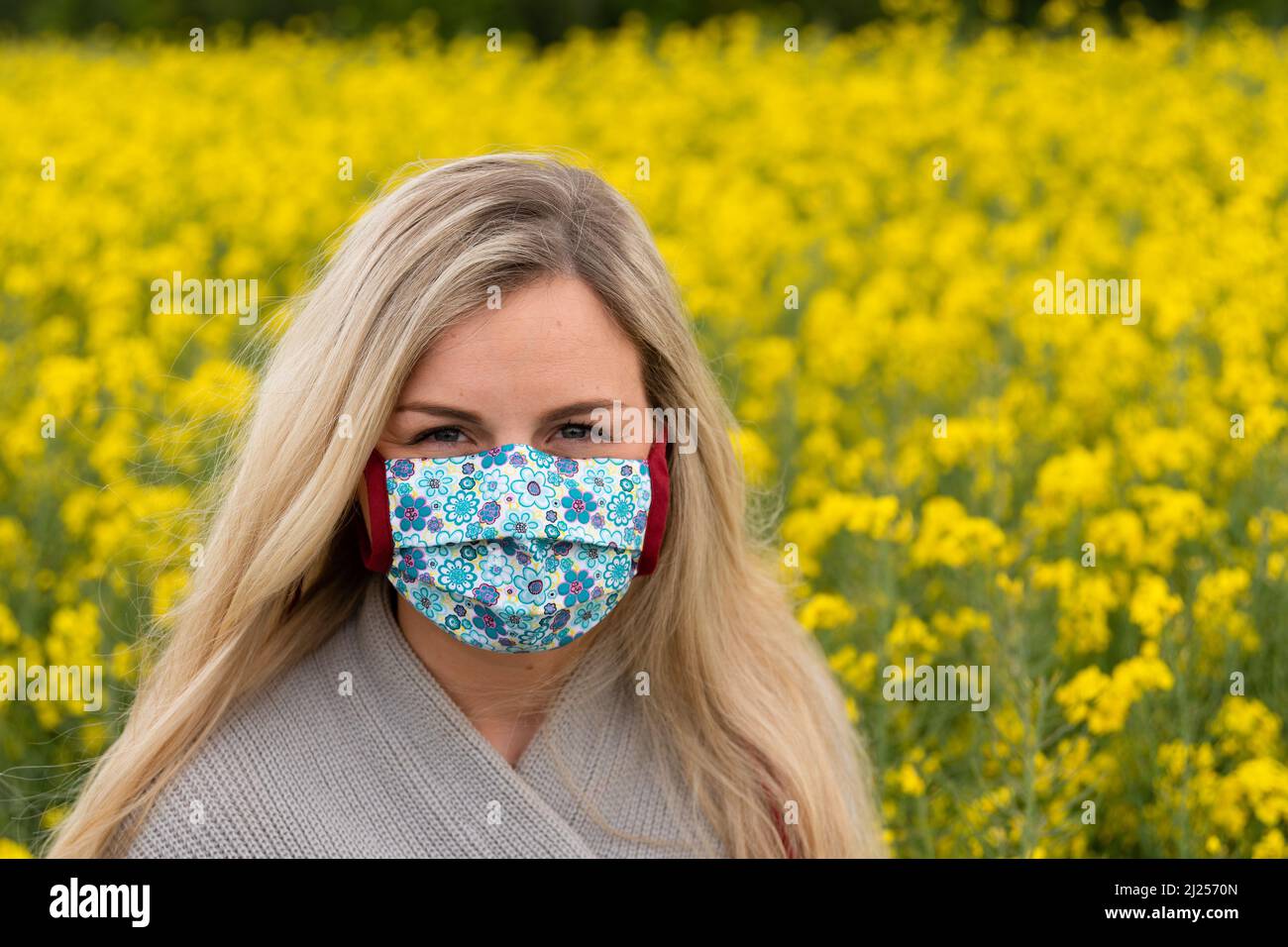 Young woman suffers from allergy, hay fever and pollen in a rape field ...