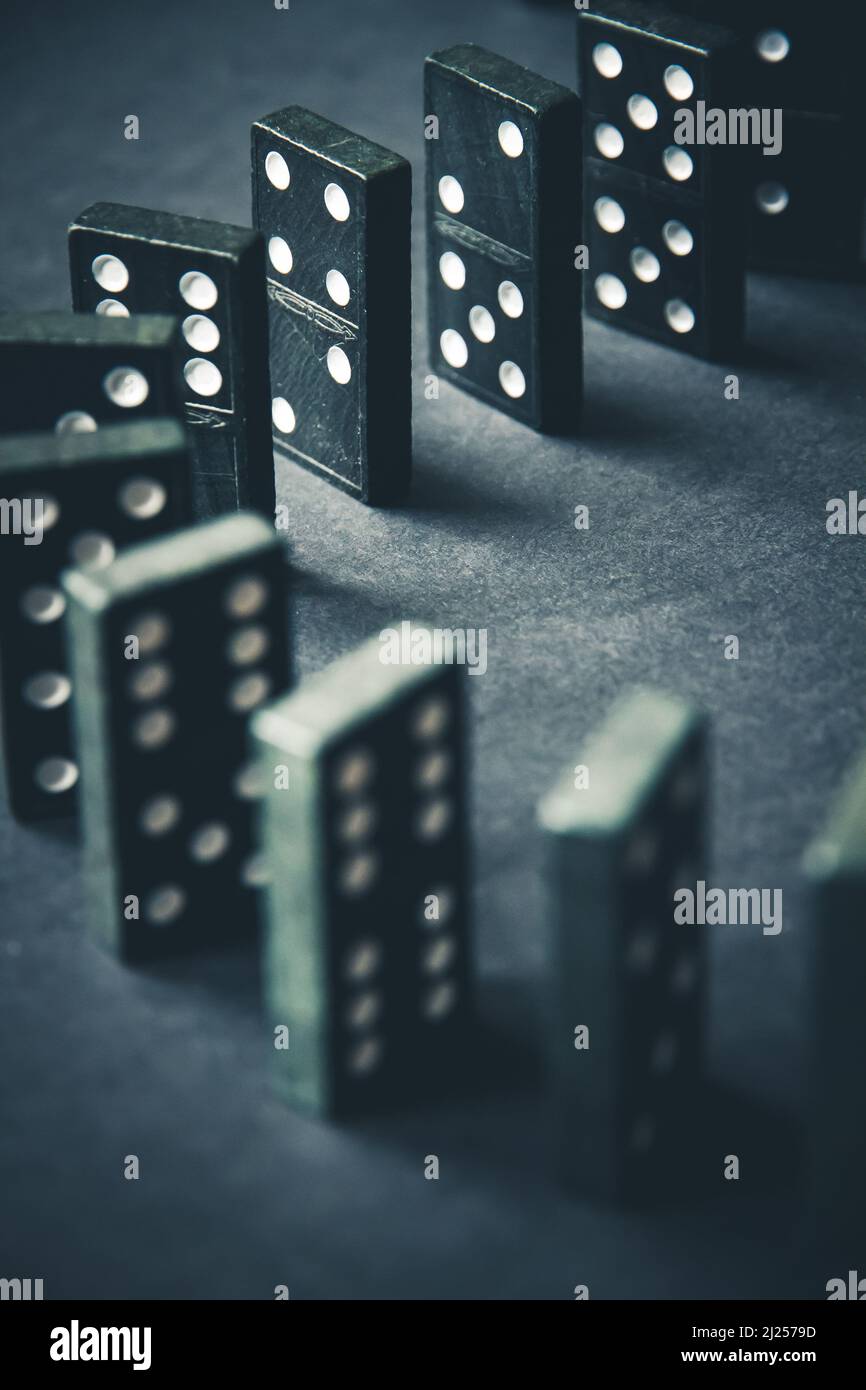 Black dominoes chain on a dark table background. Domino effect concept ...