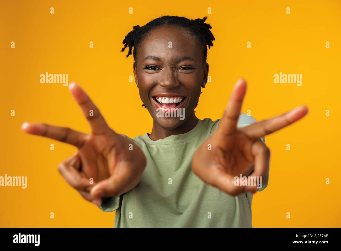 Happy black smiling woman showing v sign at studio Stock Photo - Alamy