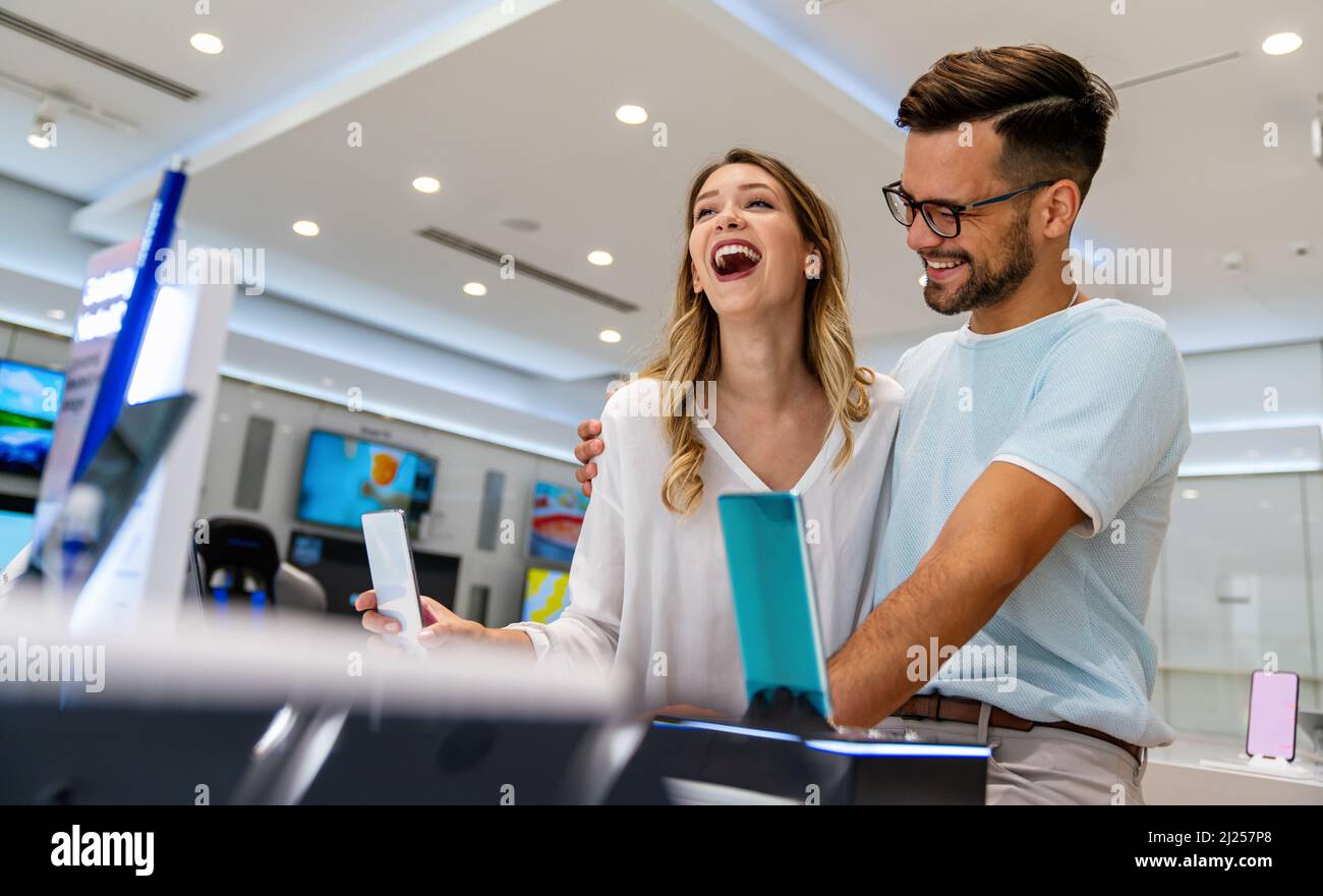 Happy young people buying new smartphone in mobile shop. Technology ...