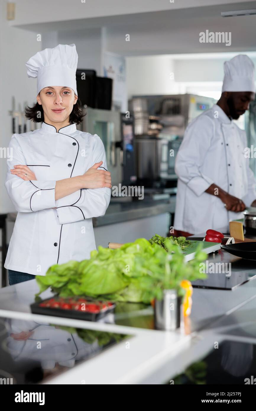 Food industry worker standing in restaurant kitchen with arms crossed ...