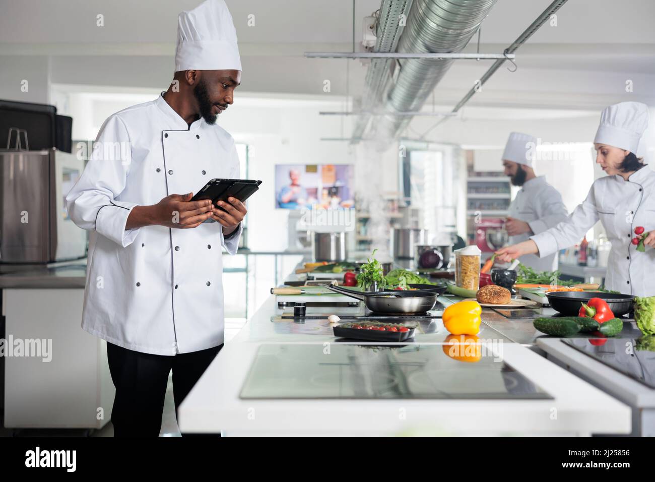 Head cook with tablet brainstorming garnish ideas for gourmet cuisine ...