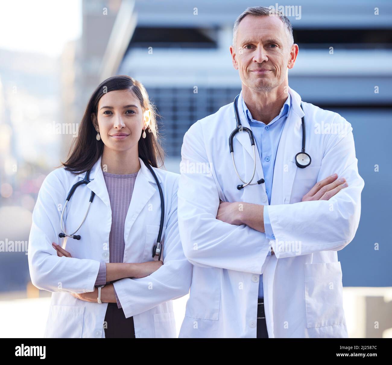 Come inside. Portrait of two doctors with folded arms outside in the ...