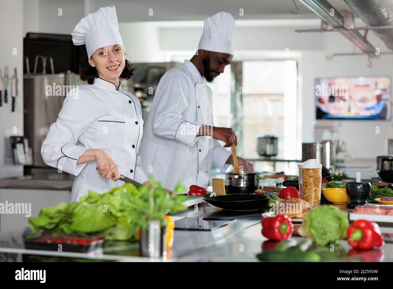 Professional cooks wearing cooking uniforms preparing fresh vegetables ...