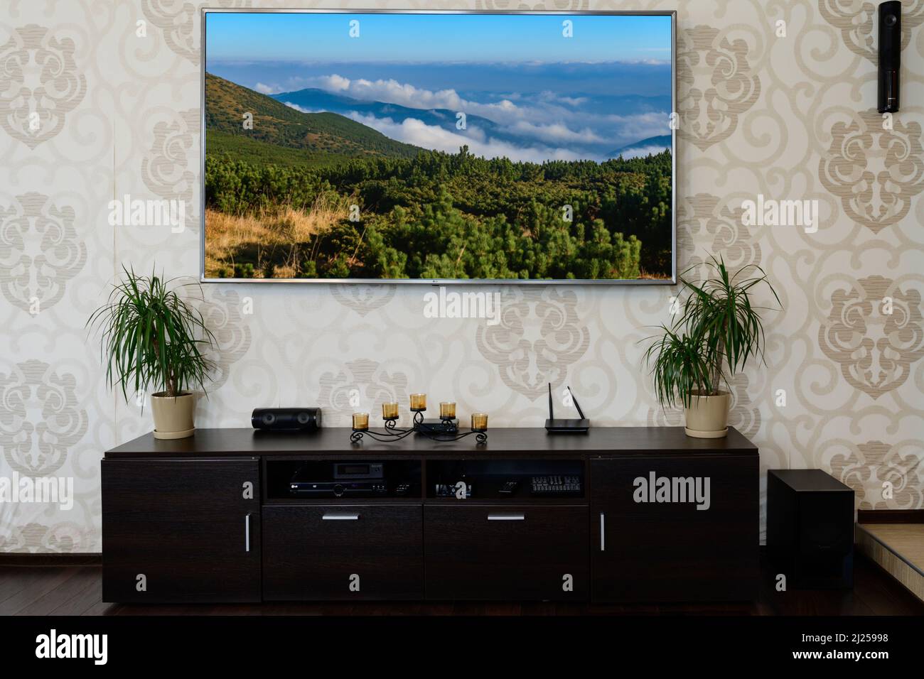 The plasma TV is attached to the wall, there is a bedside table under ...
