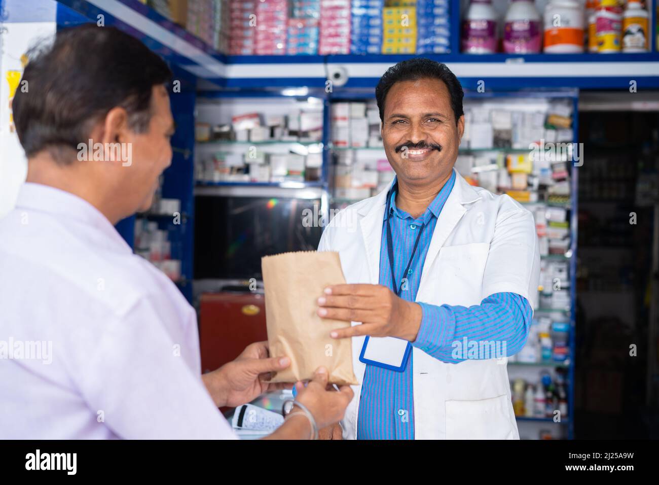 Smiling pharmacis giving medicine cover to customer at pharmacy shop ...