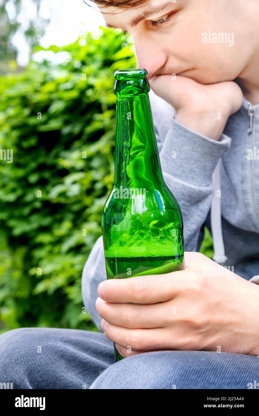 Sad Young Man hold a Beer Bottle outdoor closeup Stock Photo - Alamy