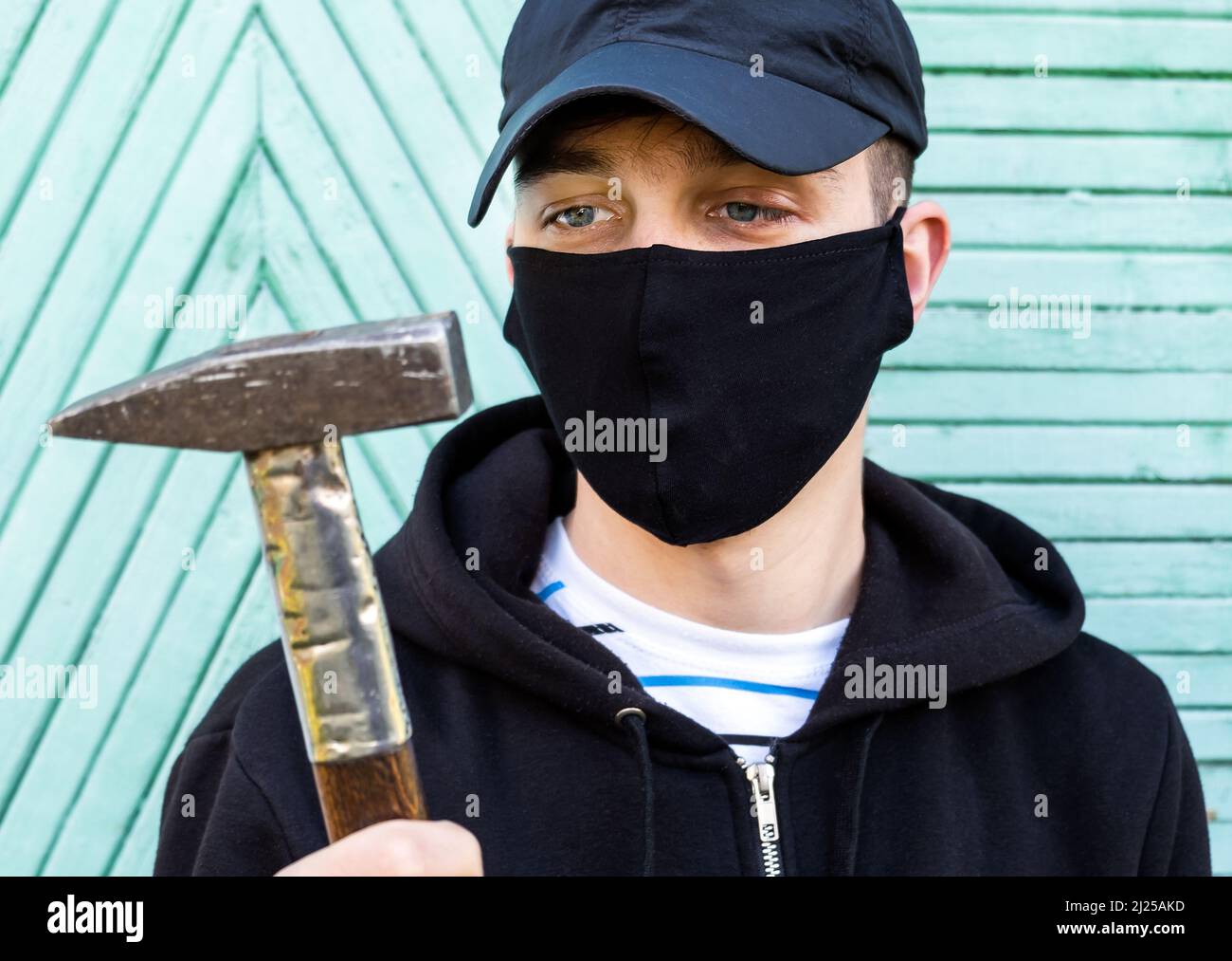 Young Man in a Flu Mask hold the Old Hammer on the Old Wall Background ...