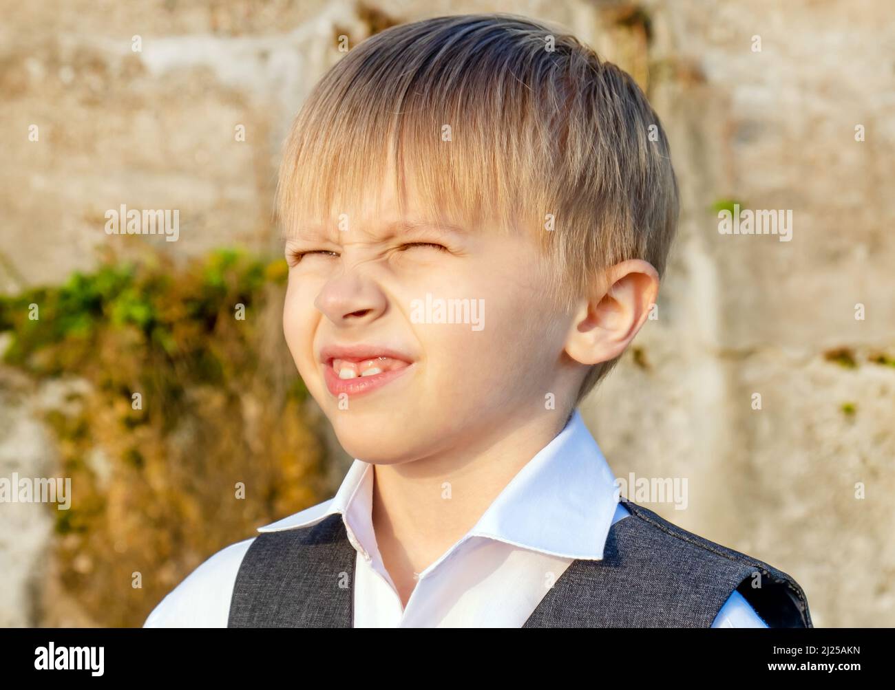 Kid squints from the Sun on the Old Wall Background outdoor Stock Photo ...