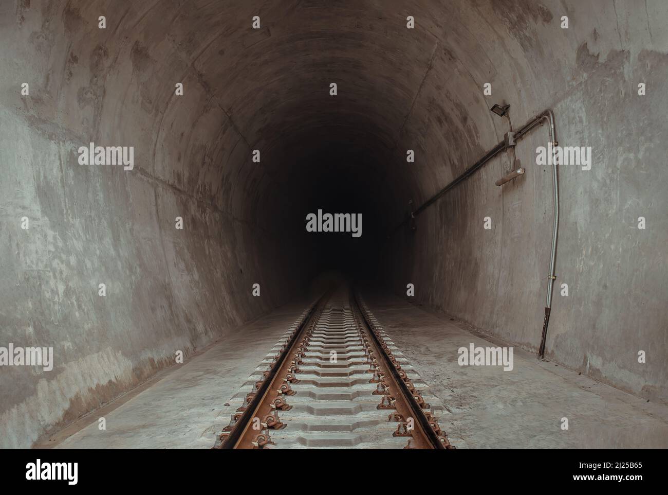 Railway track leading lines into the dark train tunnel entrance ...