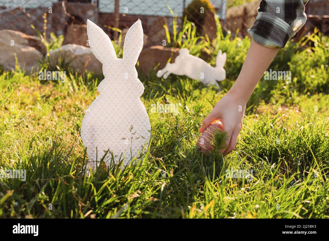 The concept of Easter holidays. The girl in orange jacket picks up a ...