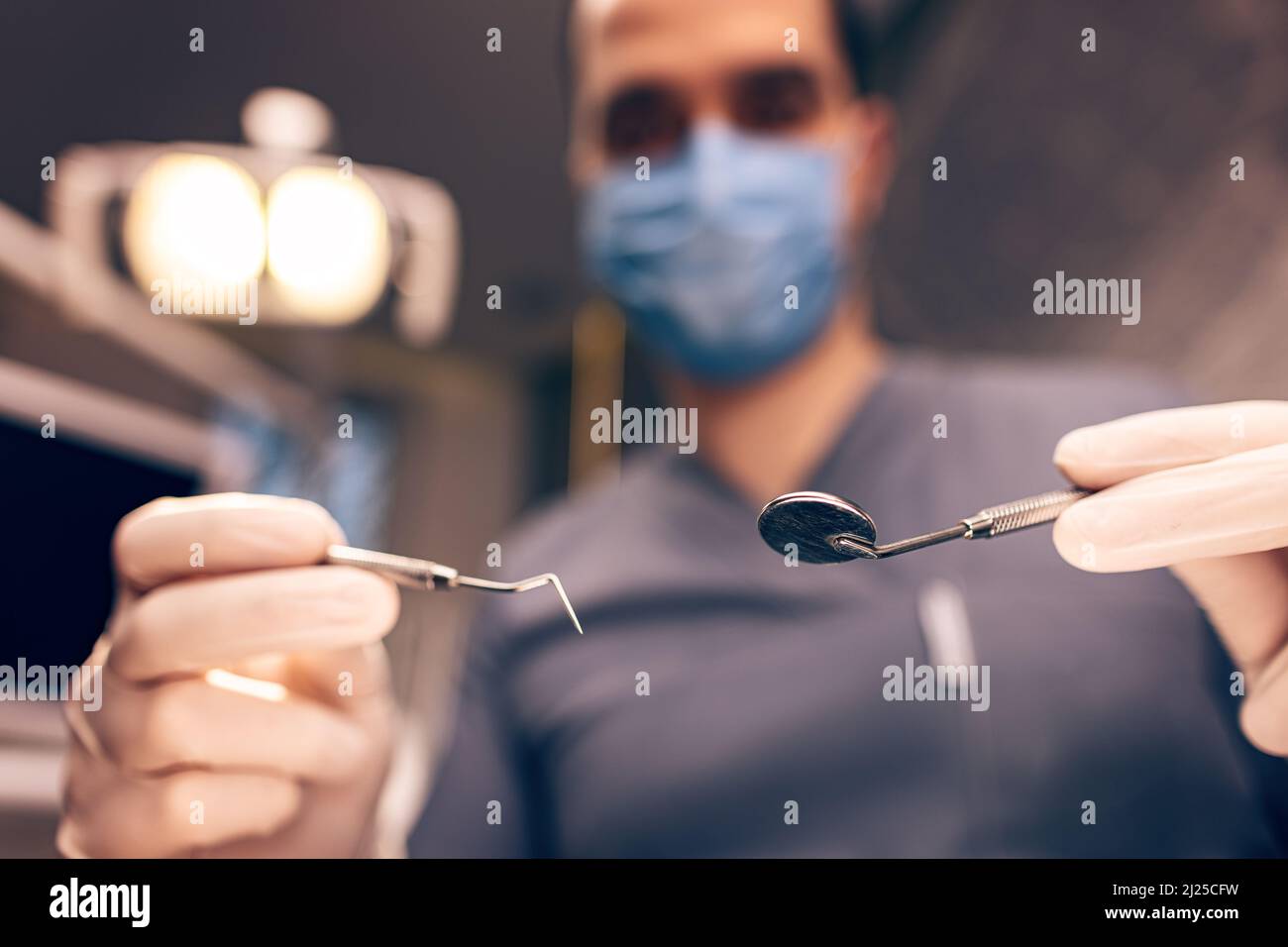 Male dentist with mirror and hook. Dentist holding dental tools Stock ...