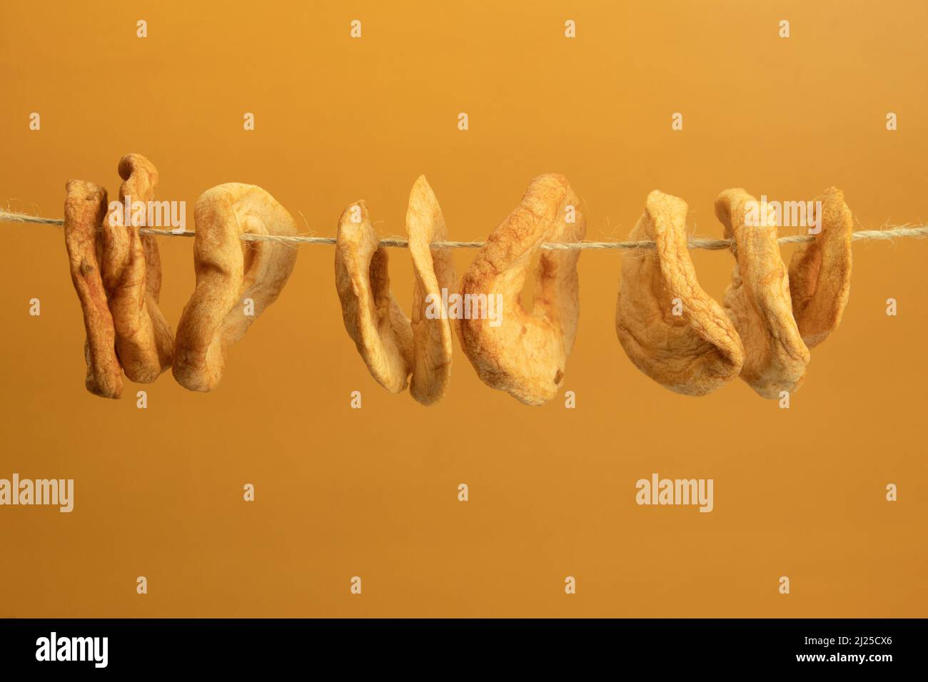 Slices of apples are dried on a rope. Background with copy space ...
