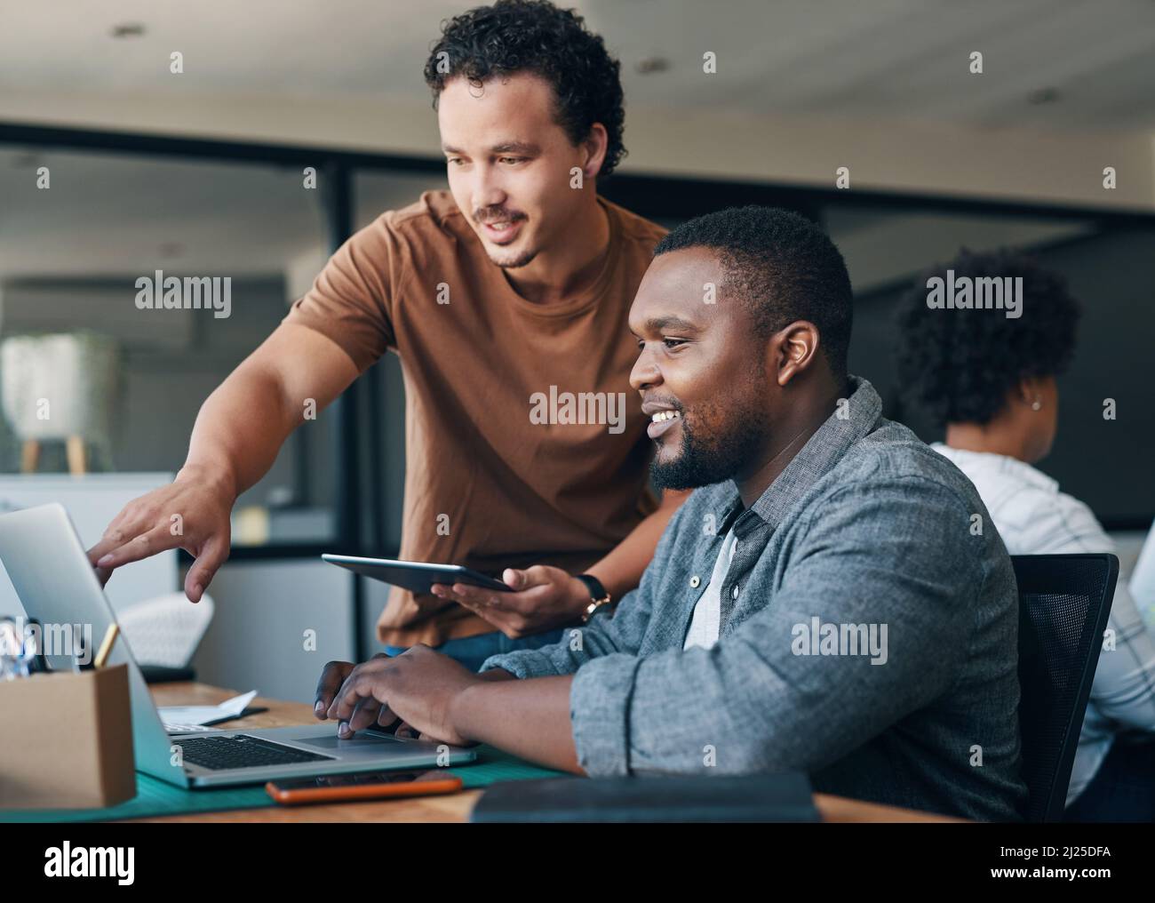 Teamwork makes everything easier. Shot of two young businessmen working ...
