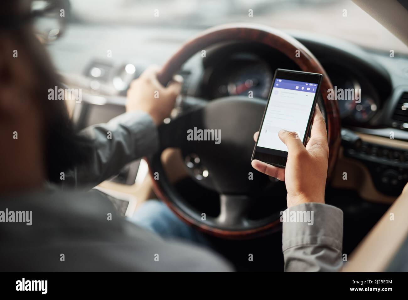 Texting and driving an accident waiting to happen. Shot of a man using ...