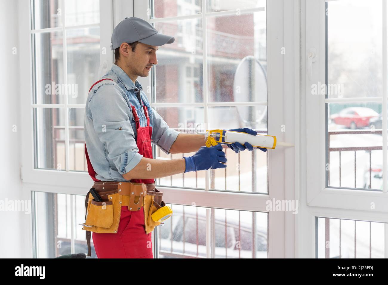handsome young man installing bay window in a new house construction ...