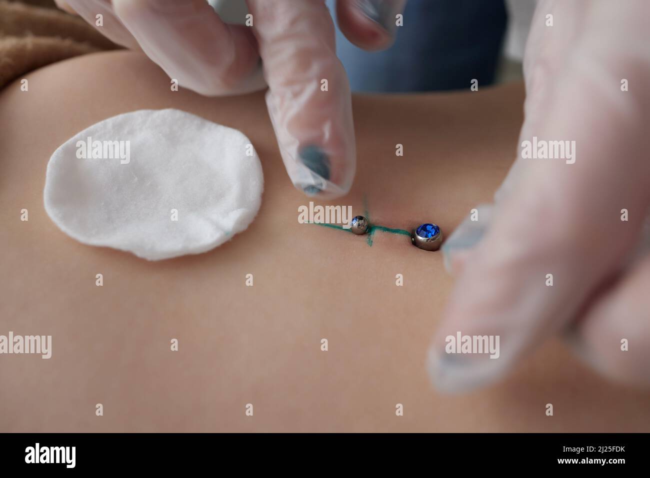 Close up of skin held in piercing tool as needle is ready to go in to ...