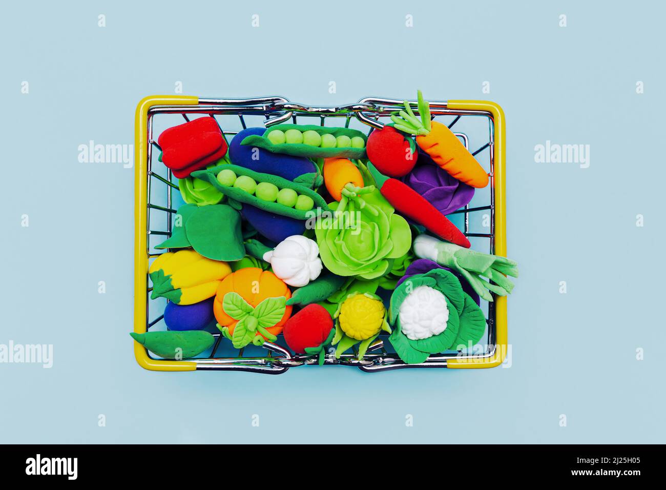 Different plasticine vegetables in a shopping basket on a blue ...