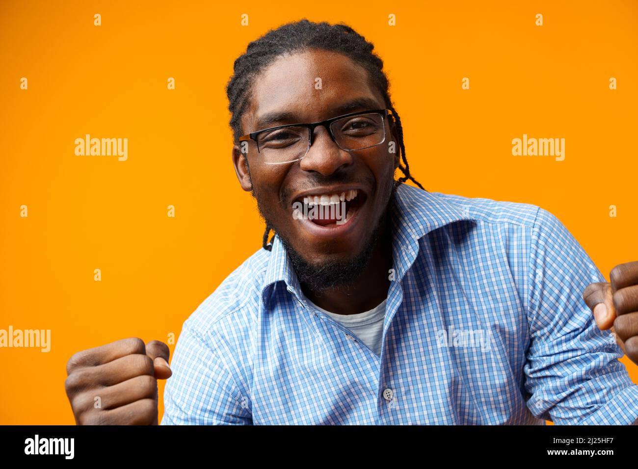 Portrait of overjoyed black man celebrating success with clenched fists ...
