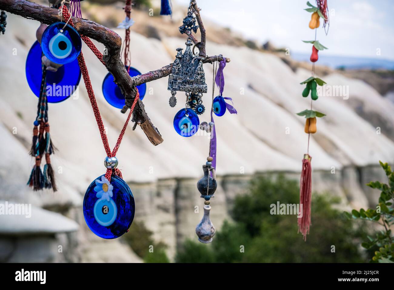 Amulets against evil eye hanging on tree in front of sandy mountain in ...