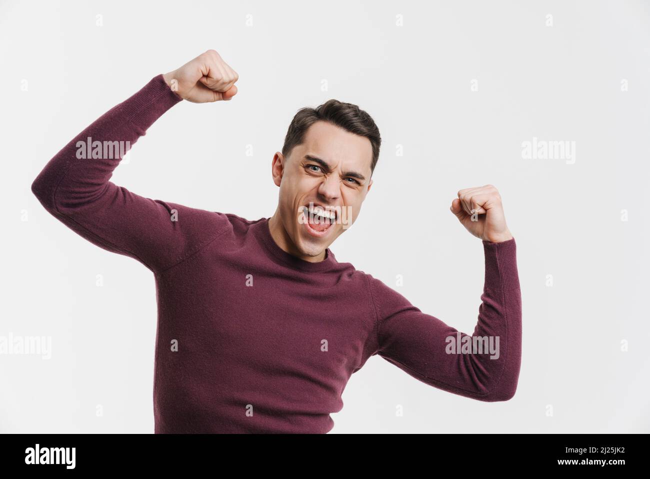 Young excited man screaming while making winner gesture isolated over ...