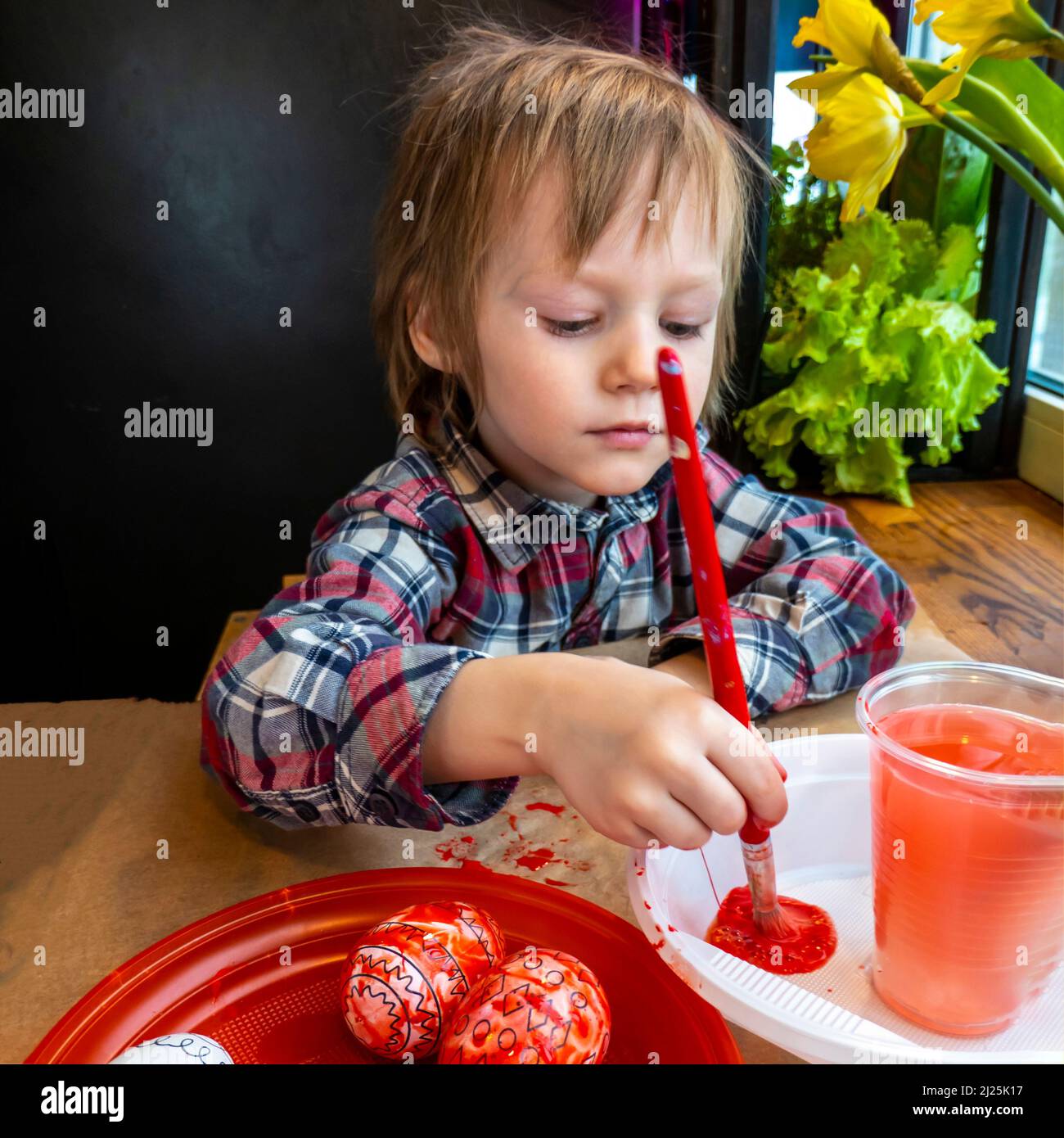 The child preparing for Easter. Paint eggs. Red paint egg Stock Photo ...
