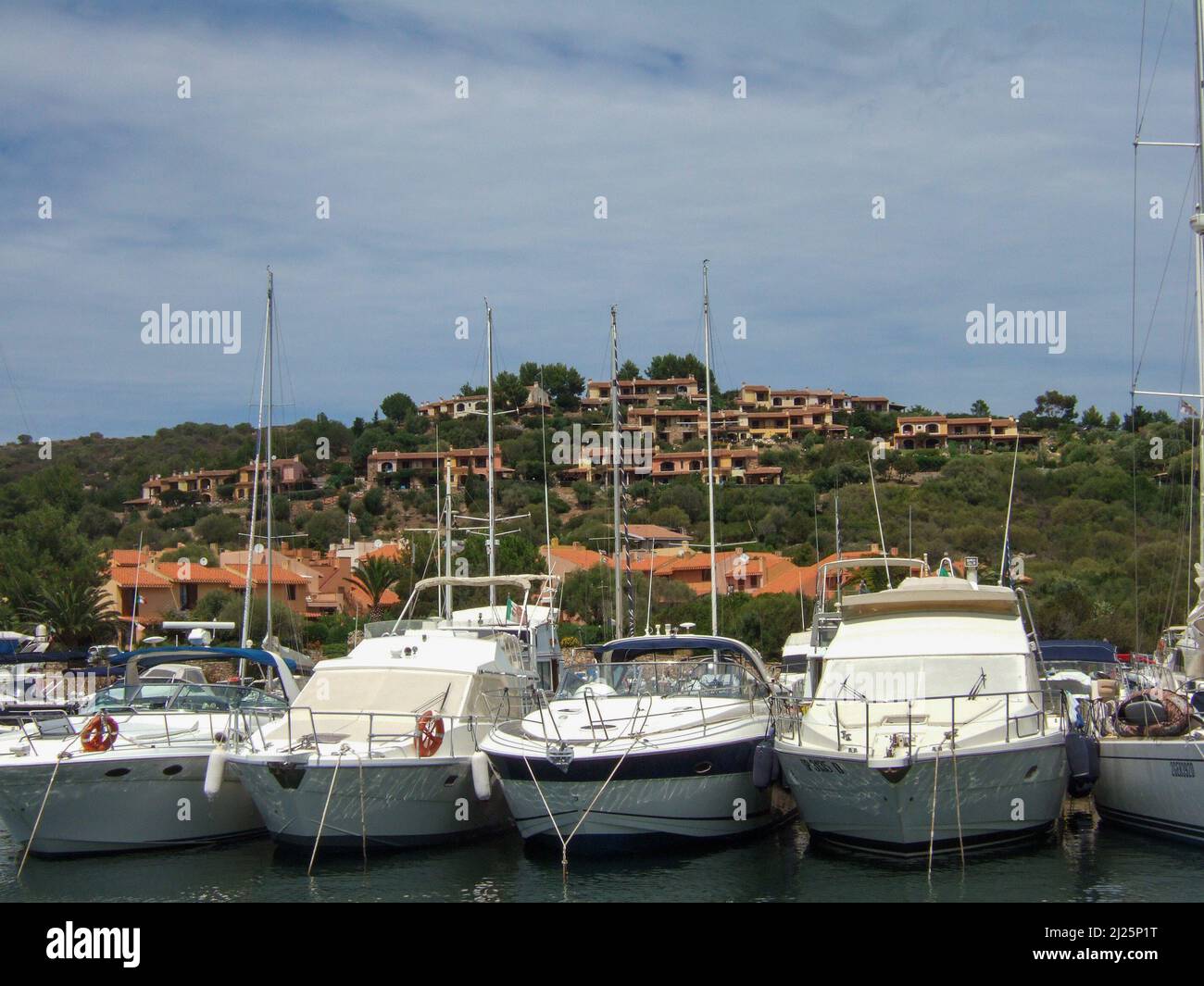 Yachts and sailboats in the port of Budoni. In the background the red ...