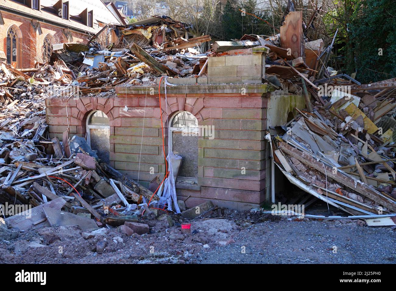 The photo shows a collapsed house surrounded by rubble and the remains ...