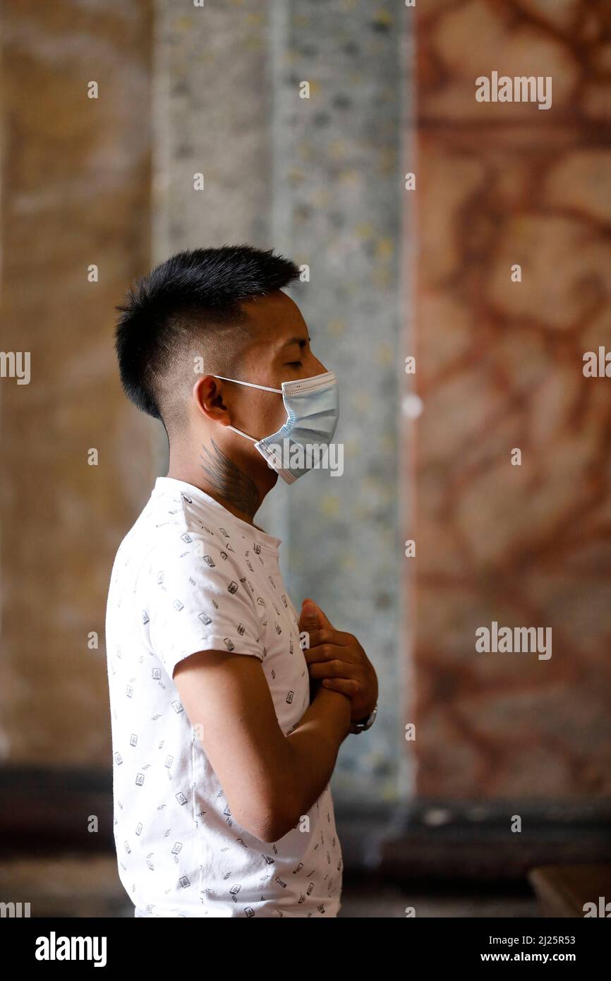 Faithful wearing a face mask and praying in Sagrario catholic church ...