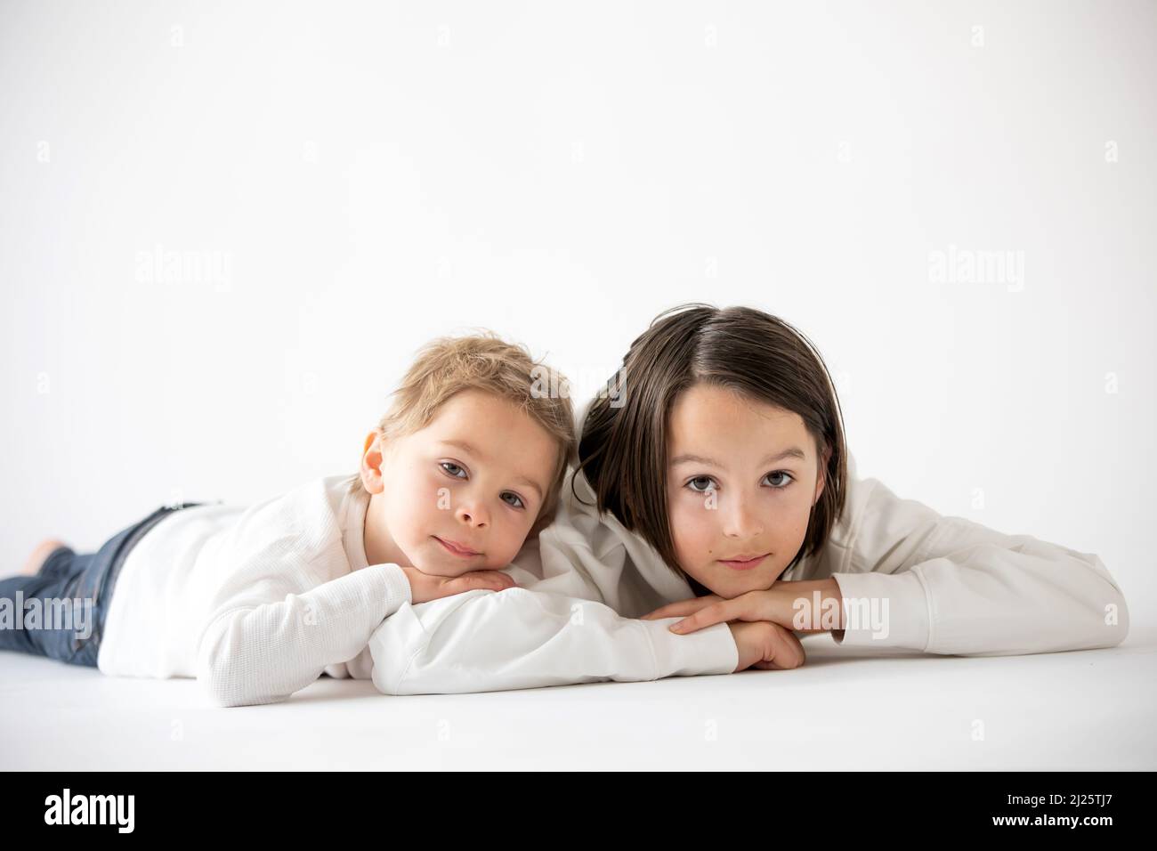 Cute stylish toddler child and older brother, boys with white shirts on ...