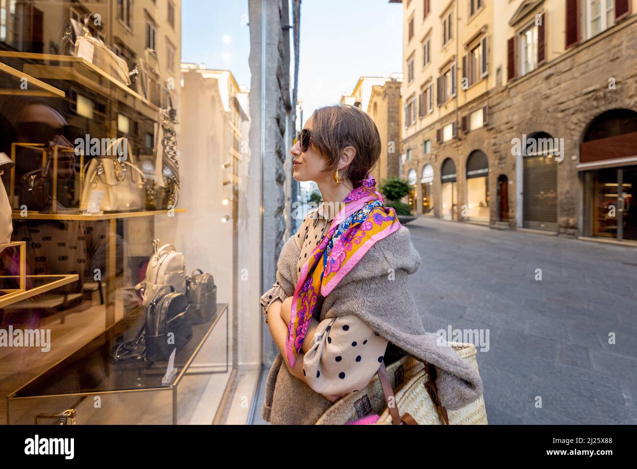 Woman looks on a showcase with bags on the street in old town Stock ...