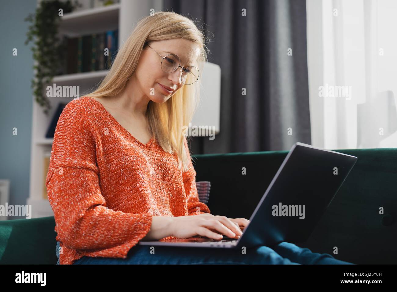 Woman with laptop on couch Stock Photo - Alamy