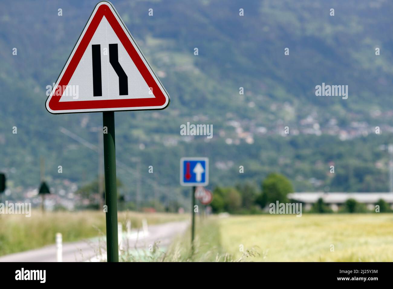 Triangular road narrowing sign on country side road Stock Photo - Alamy