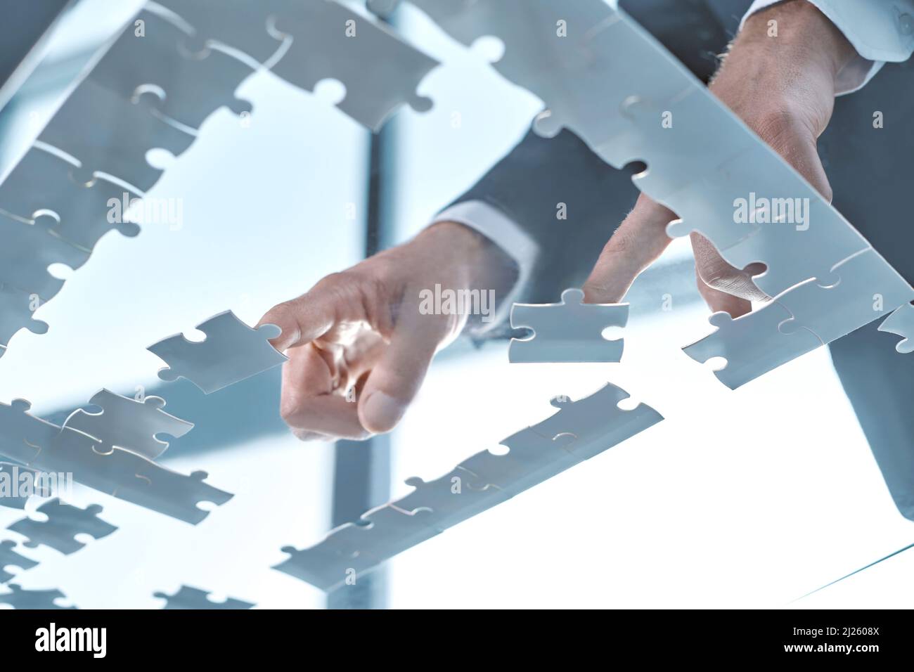 image of a businessman collecting puzzle pieces on an office desk Stock ...