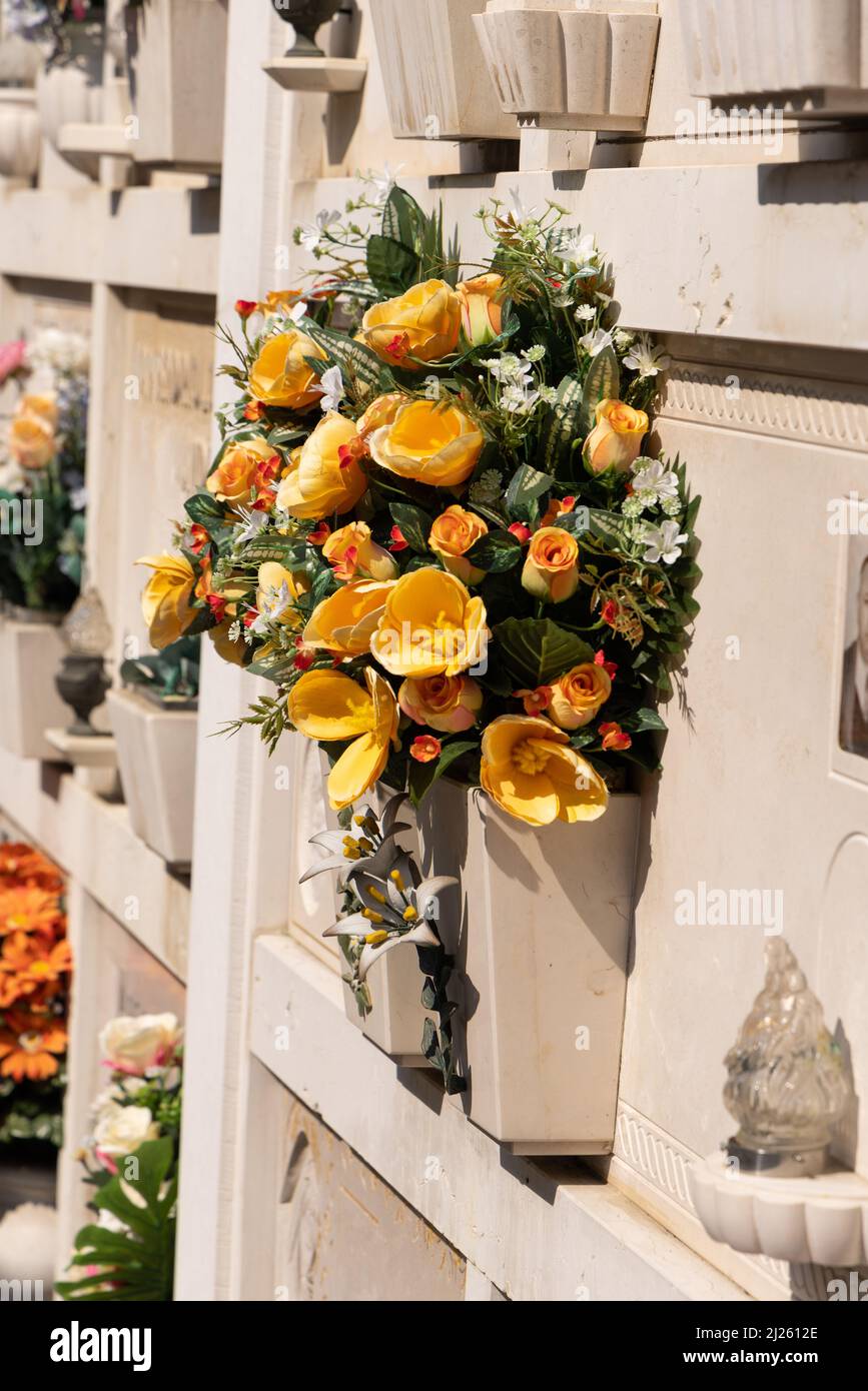 Italian wall cemetery with tombstones and artificial flowers on a sunny ...