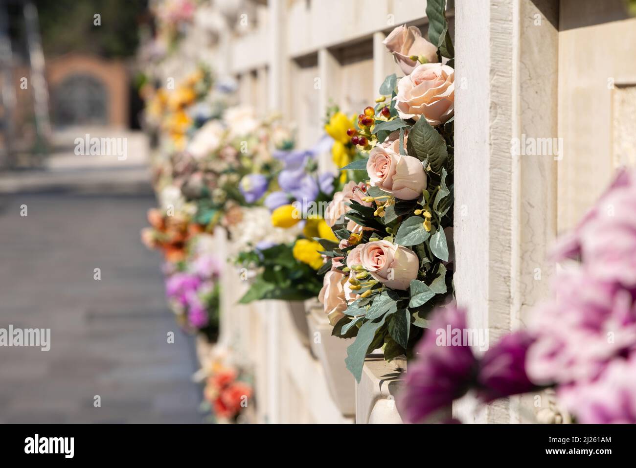 Italian wall cemetery with tombstones and artificial flowers on a sunny ...