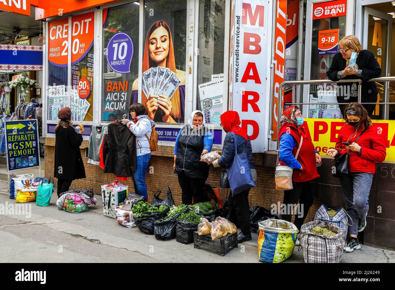 Women selling goods on a street outside the central market in Chisinau ...