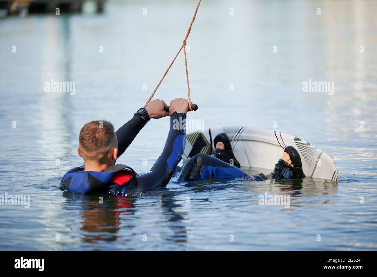 Wakeboarder surfing on lake. Back view of male surfer having fun ...