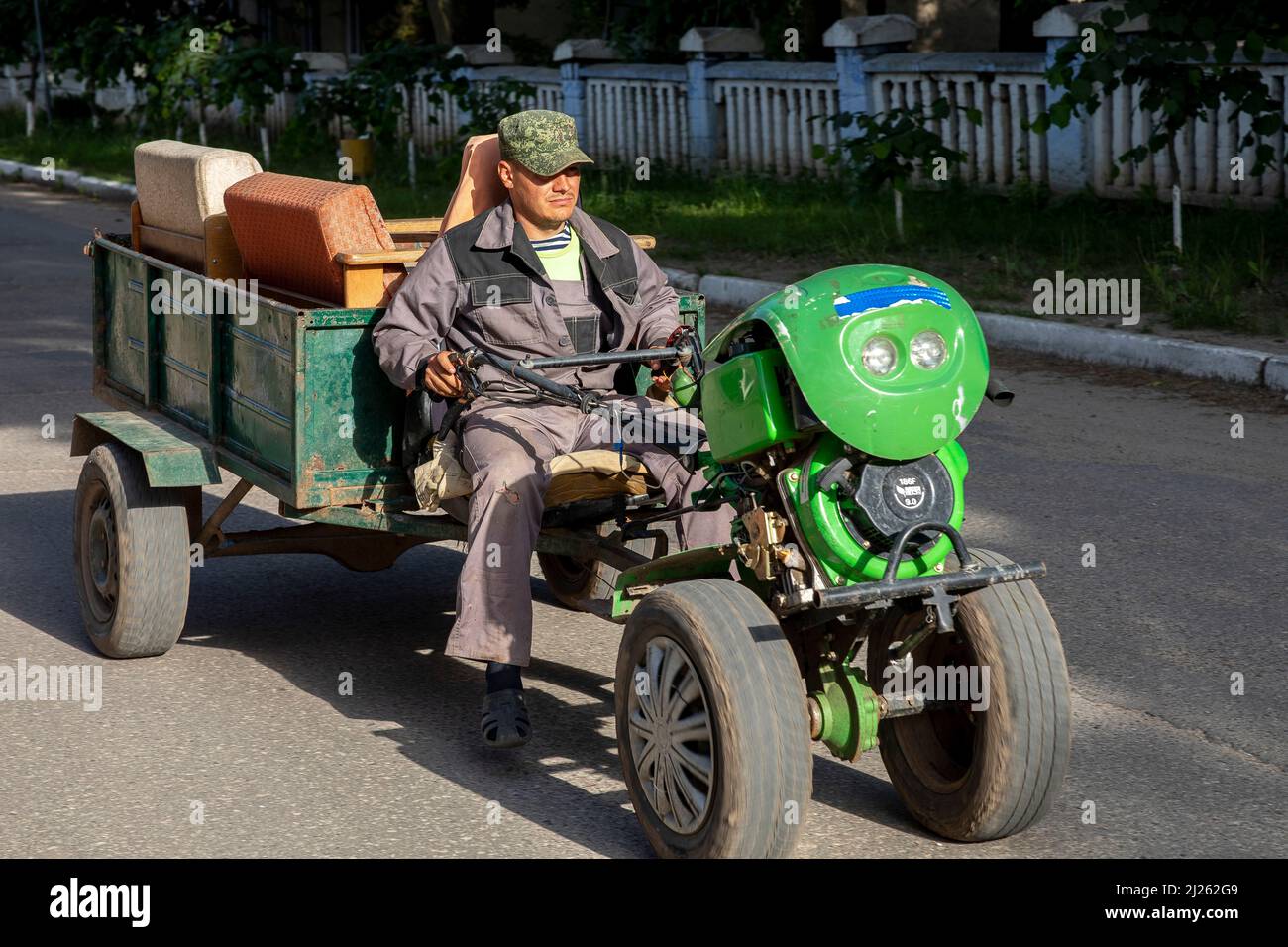 Man riding a tractor fitted with a trailer in a village near Soroca ...